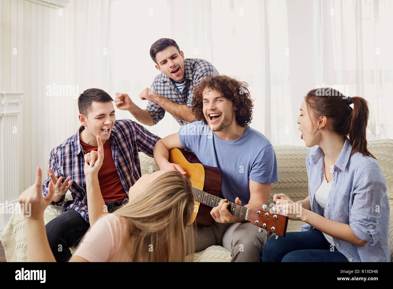 A group of friends with a guitar sing songs at a party indoor Stock ...