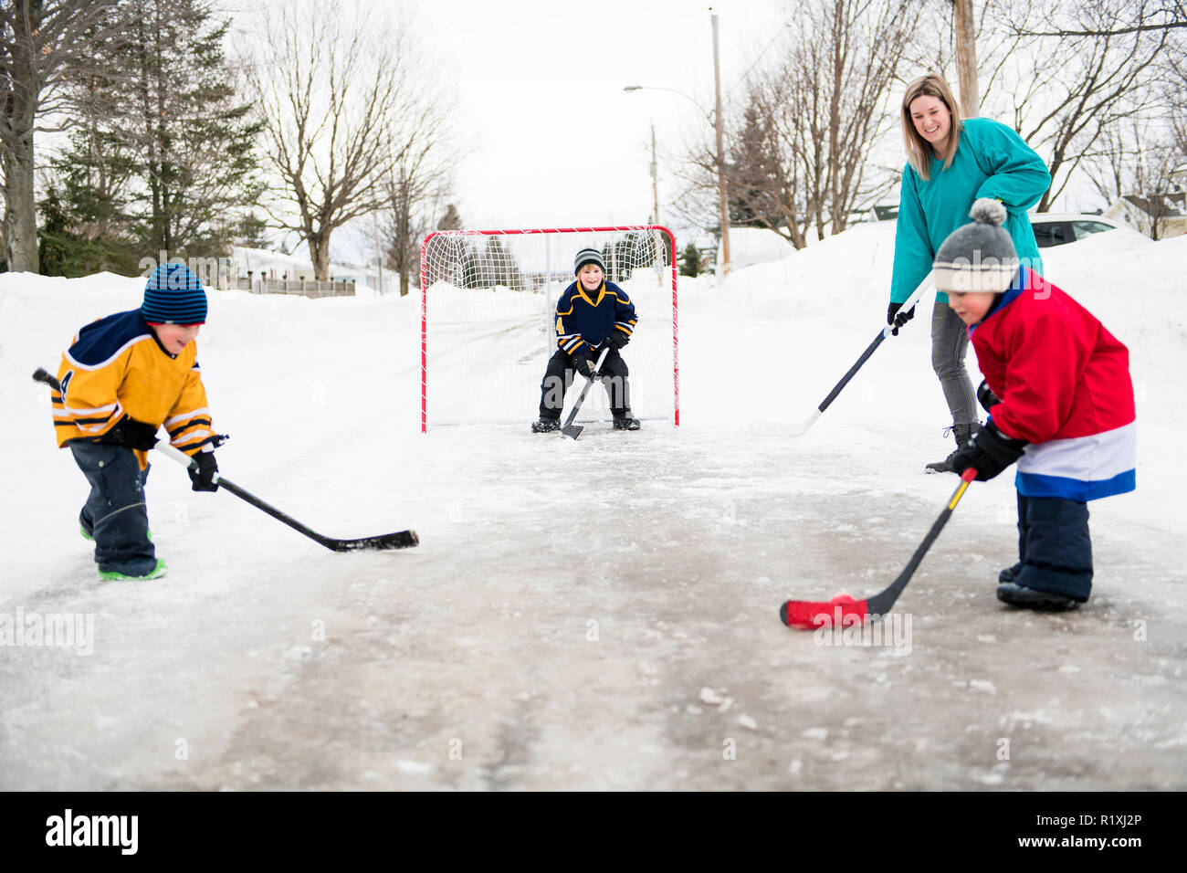 A Happy funny kids playing hockey with father on street in the winter ...