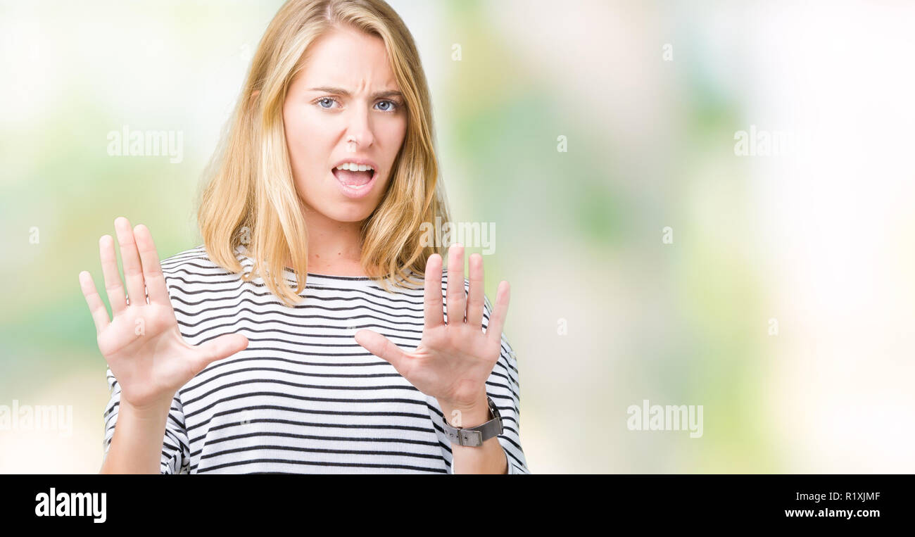 Beautiful young woman wearing stripes sweater over isolated background ...