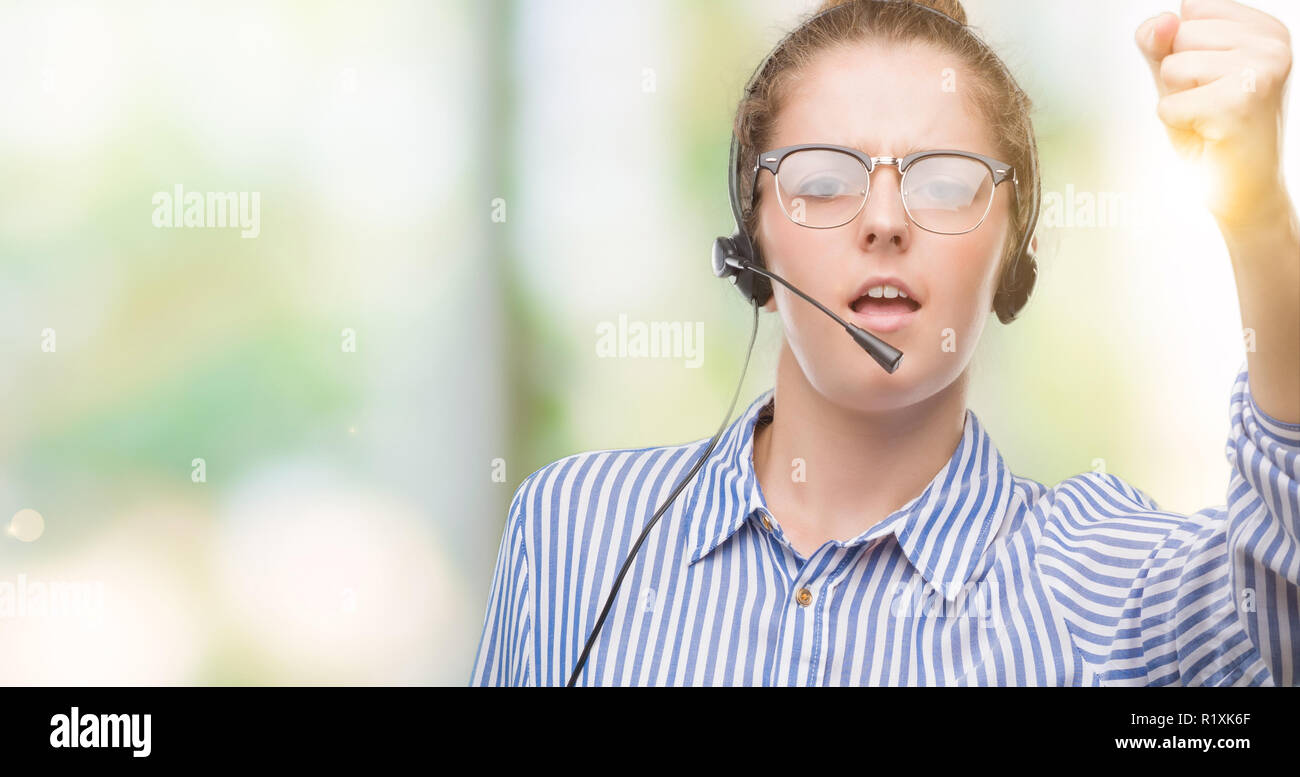 Young blonde call center operator woman annoyed and frustrated shouting ...