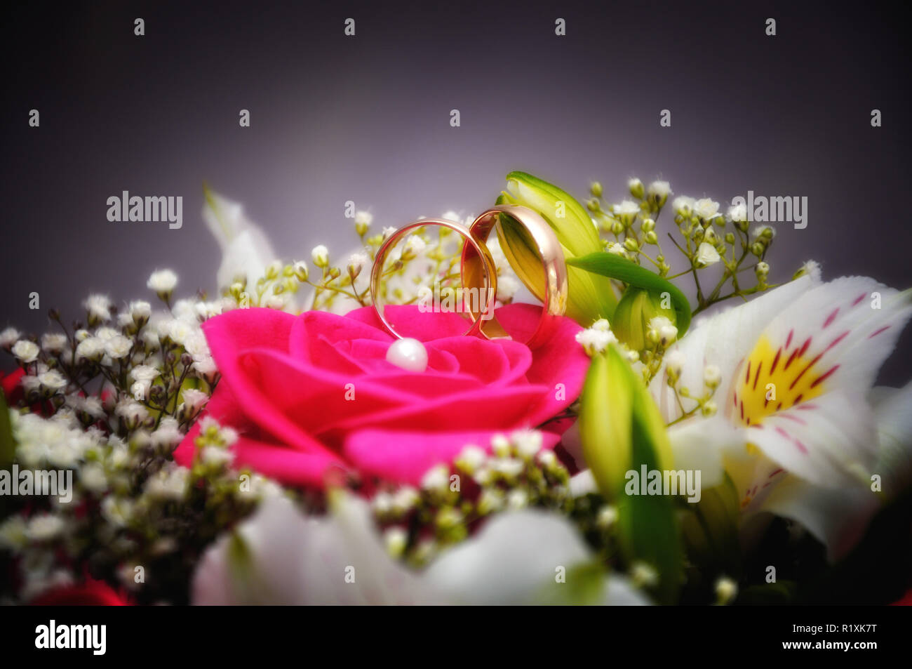 Golden wedding ring with pink roses and white lilies close-up Stock ...