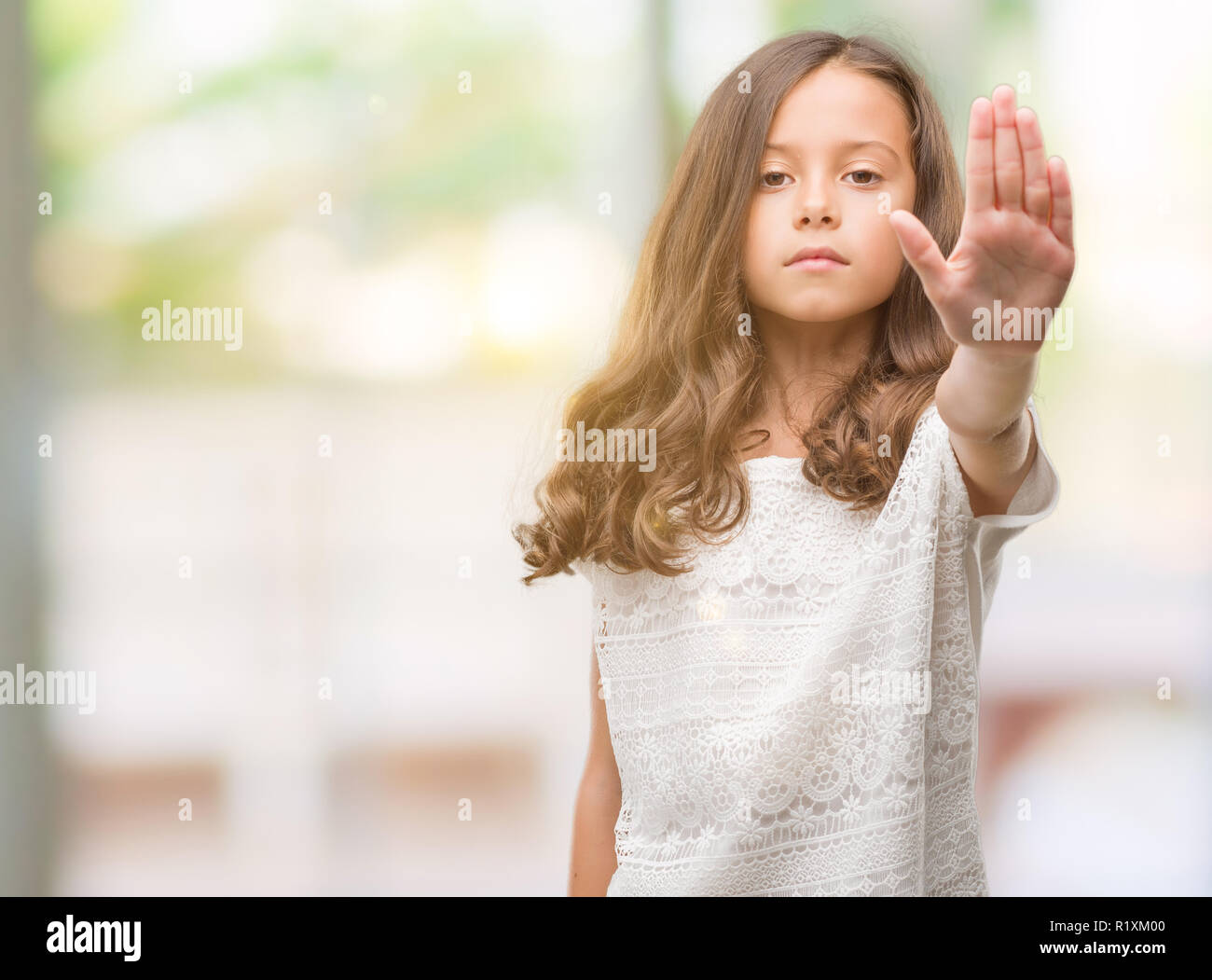 Brunette hispanic girl doing stop sing with palm of the hand. Warning ...