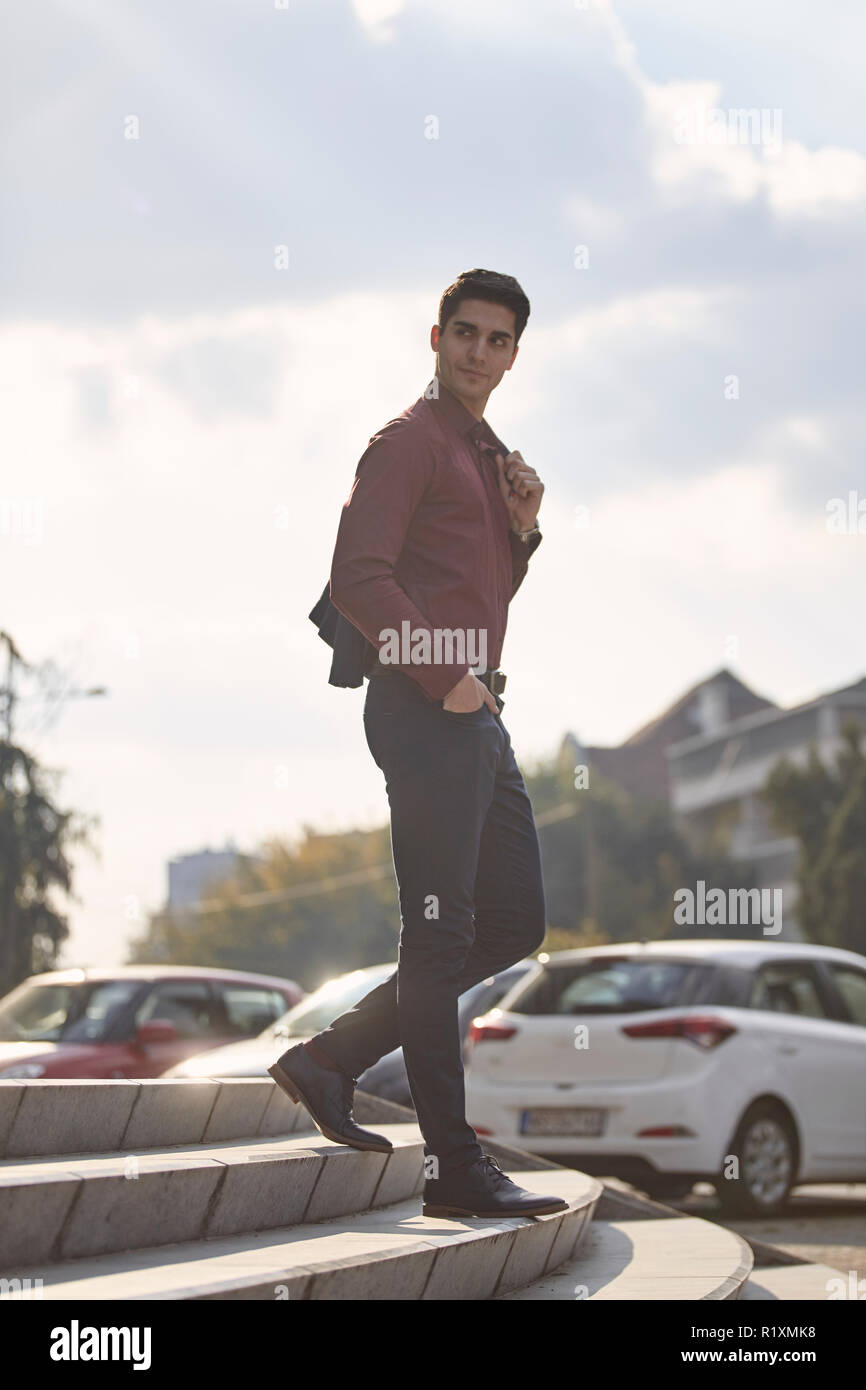 one young man, walking down steps, wearing suit. sunny day outdoors ...
