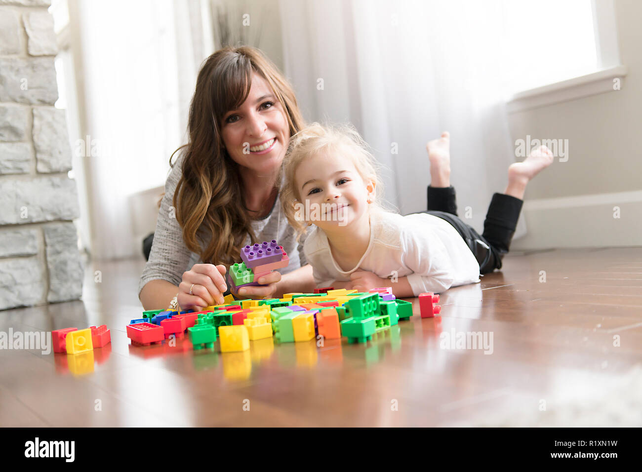A Mother and child daughter building from toy blocks at home Stock ...
