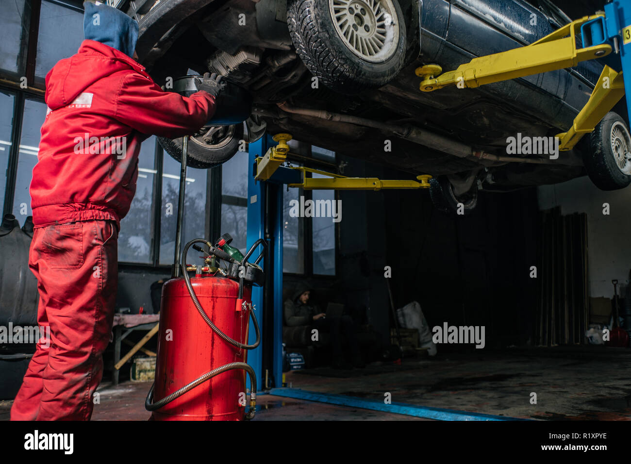 Young caucasian man in red work clothing repairing car with ...