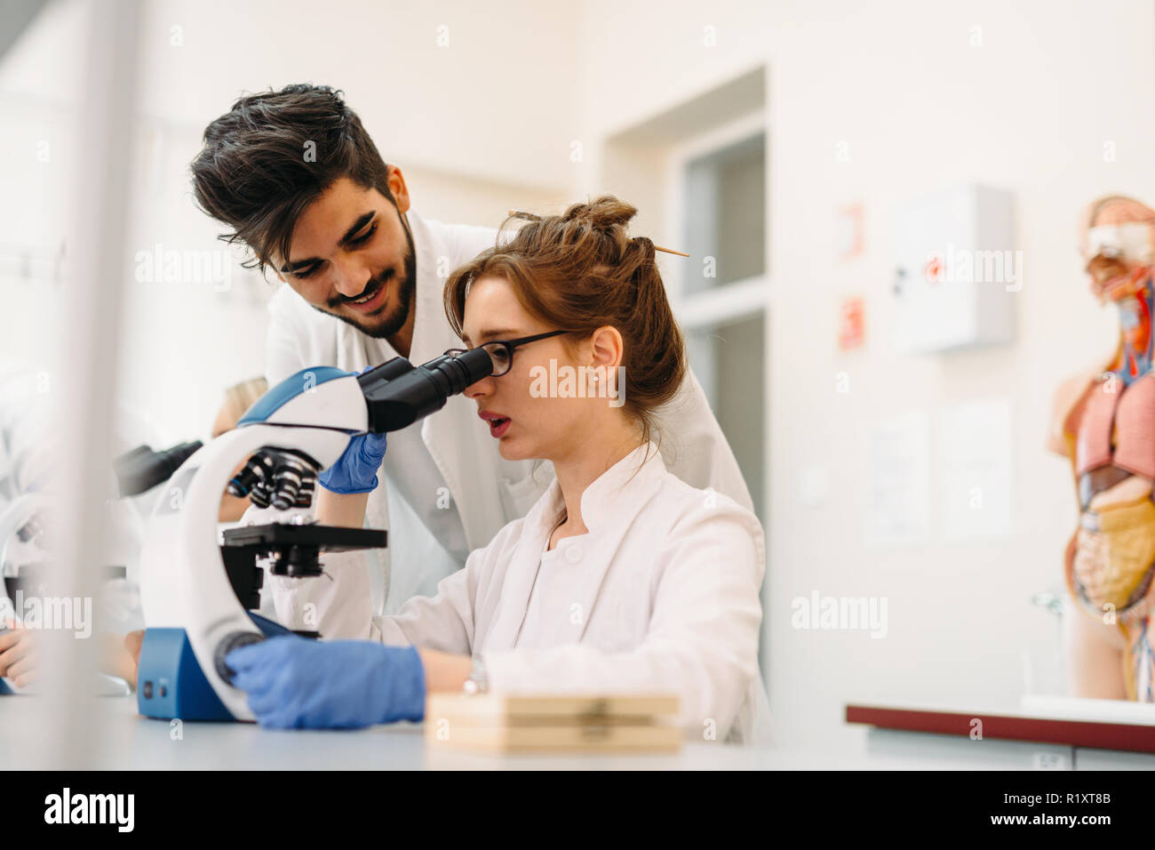 Young scientist looking through microscope in laboratory Stock Photo ...
