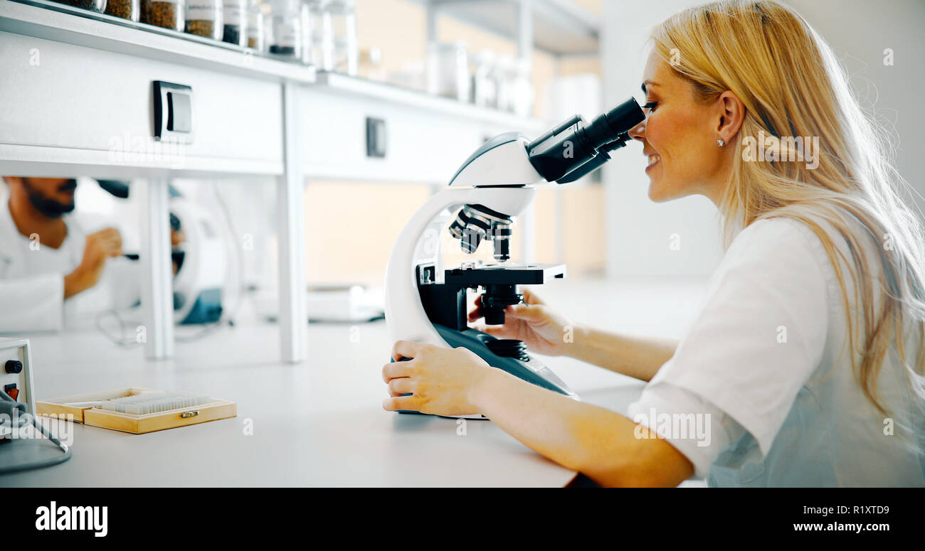 Young scientist looking through microscope in laboratory Stock Photo ...