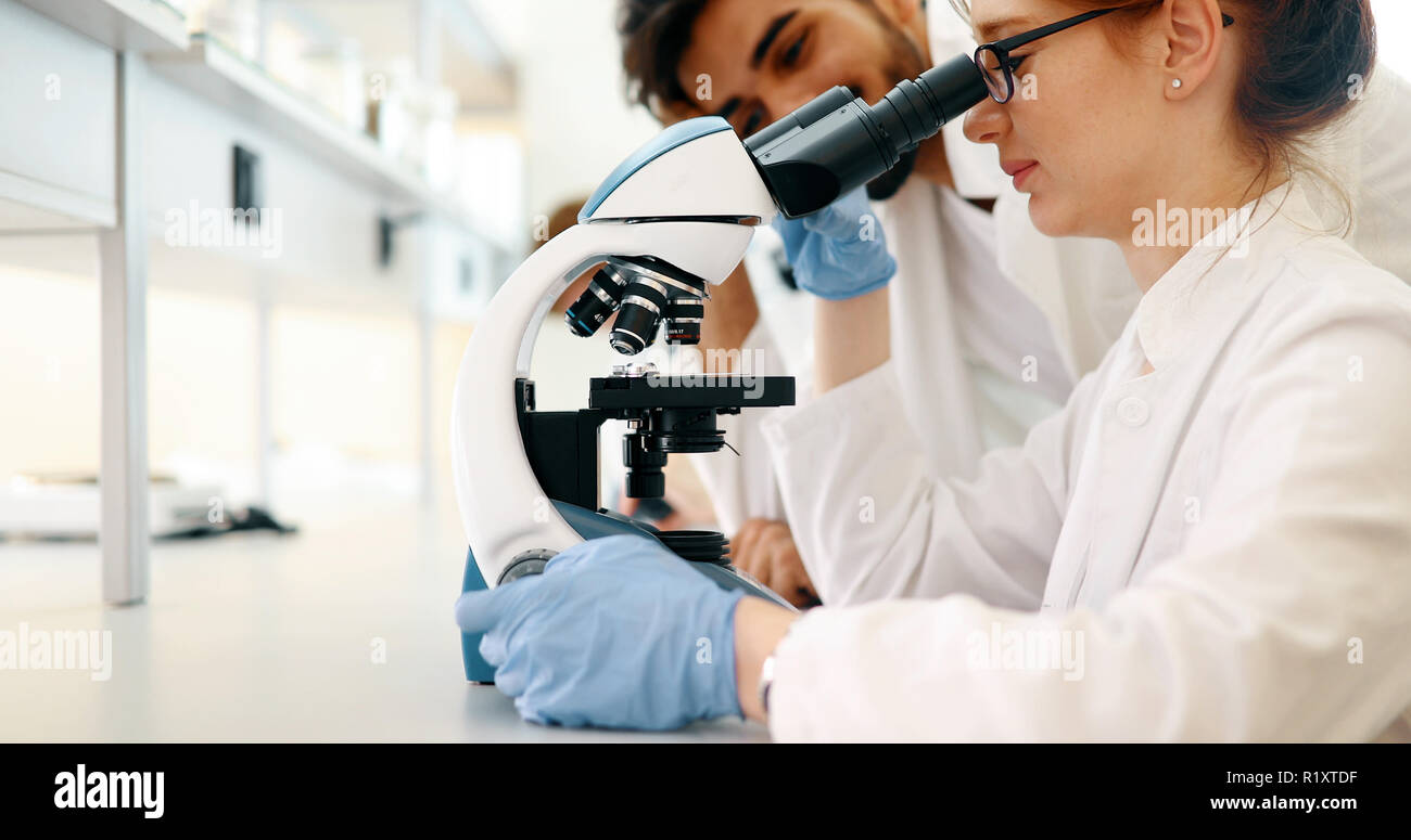 Young scientist looking through microscope in laboratory Stock Photo ...