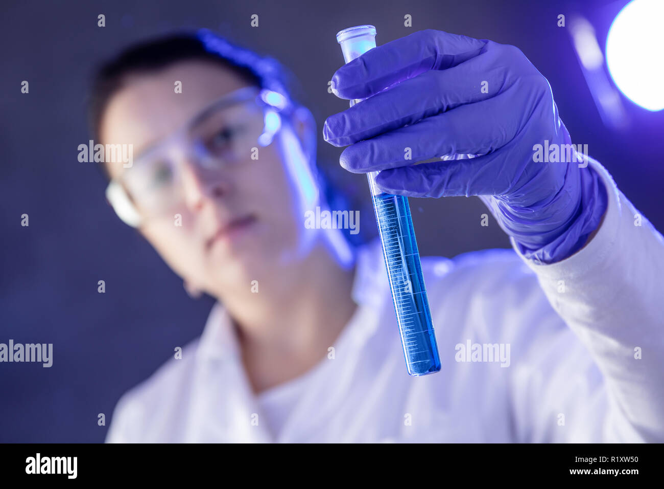Chemist's hand holding test tube with blue liquid. Horizontal view ...