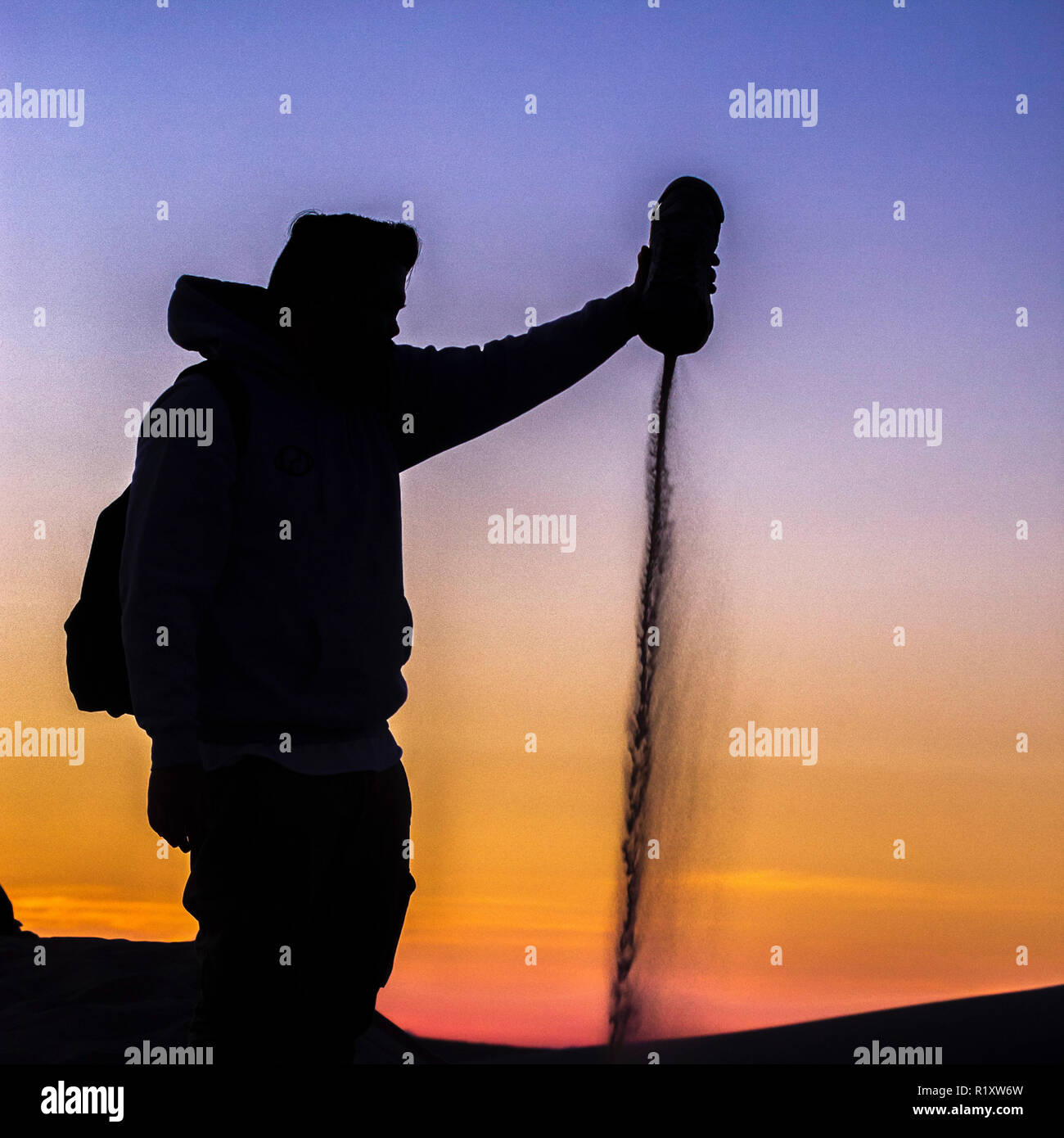 Man with can of sand spilling into the sand dunes Stock Photo - Alamy