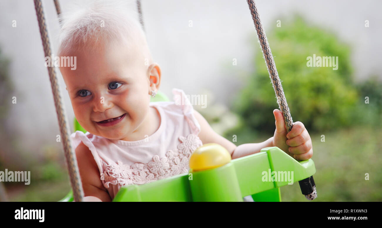 Happy baby enjoying outdoor activities and smiling while swinging Stock ...