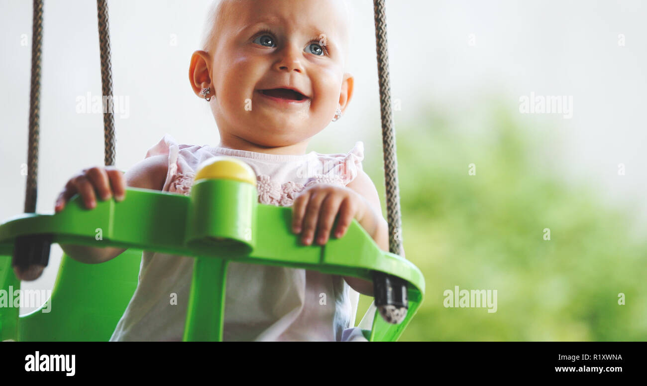 Happy baby enjoying outdoor activities and smiling while swinging Stock ...