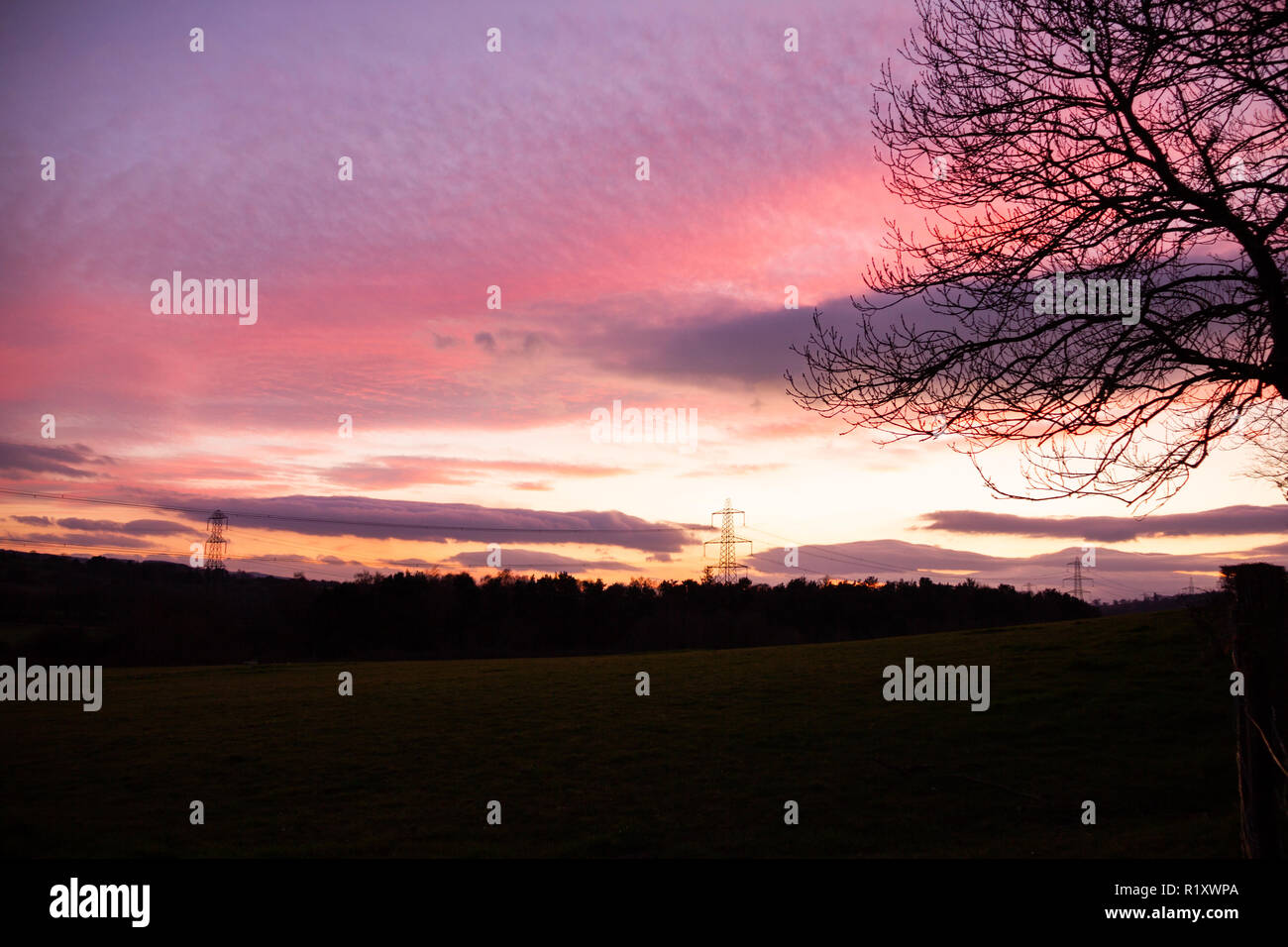 Purple sky sunset over the silhouetted countryside with power pylons ...
