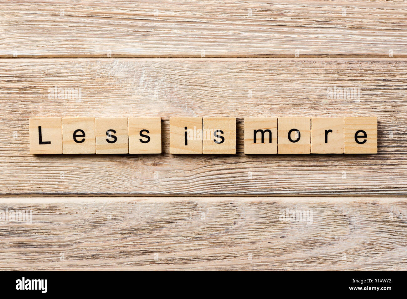 less is more word written on wood block. less is more text on table ...