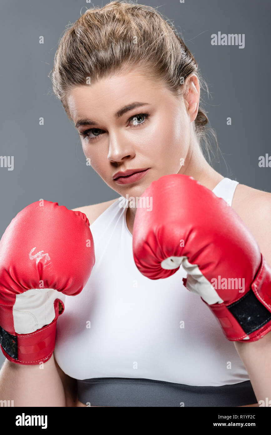 beautiful young woman in boxing gloves looking at camera isolated on ...