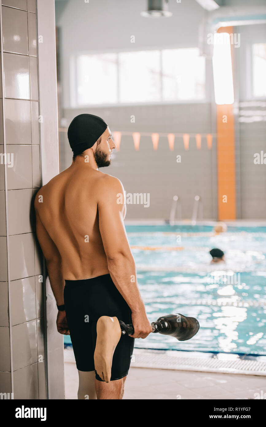 rear view of swimmer standing at poolside of indoor swimming pool and ...