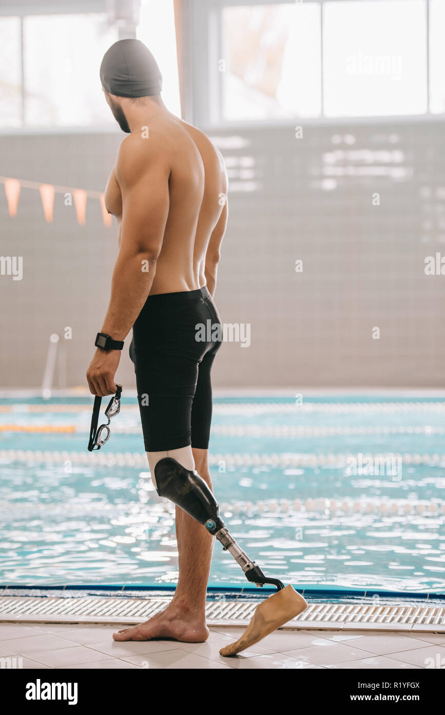 handsome young swimmer with artificial leg walking on poolside of ...