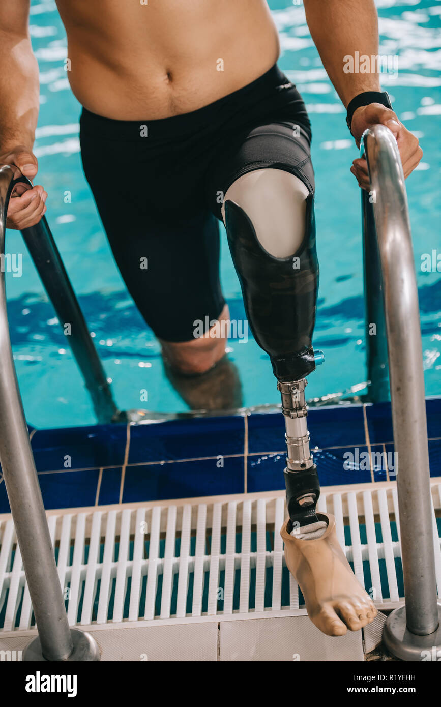 cropped shot of fit swimmer with artificial leg getting out of swimming ...