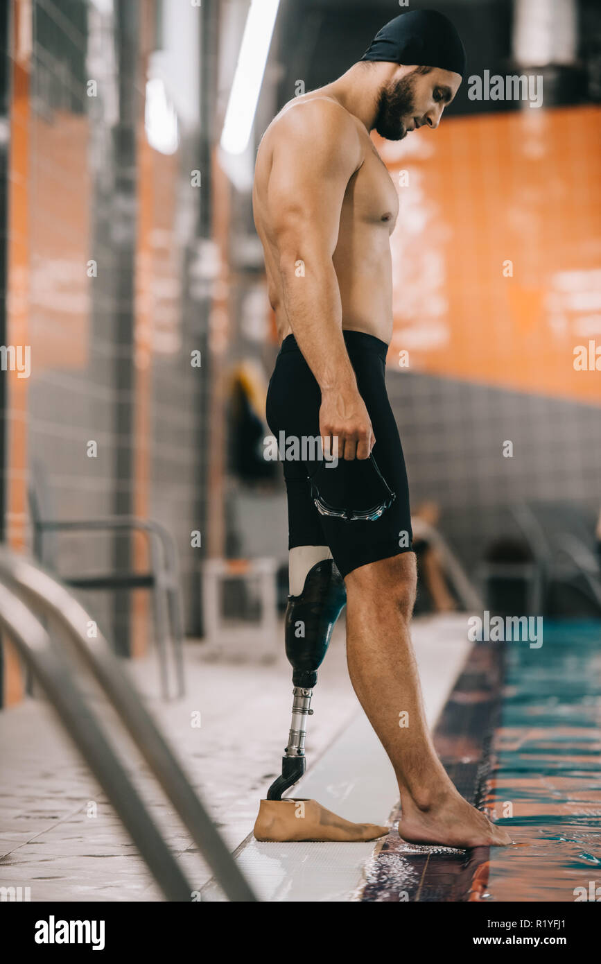handsome young swimmer with artificial leg standing on poolside at ...