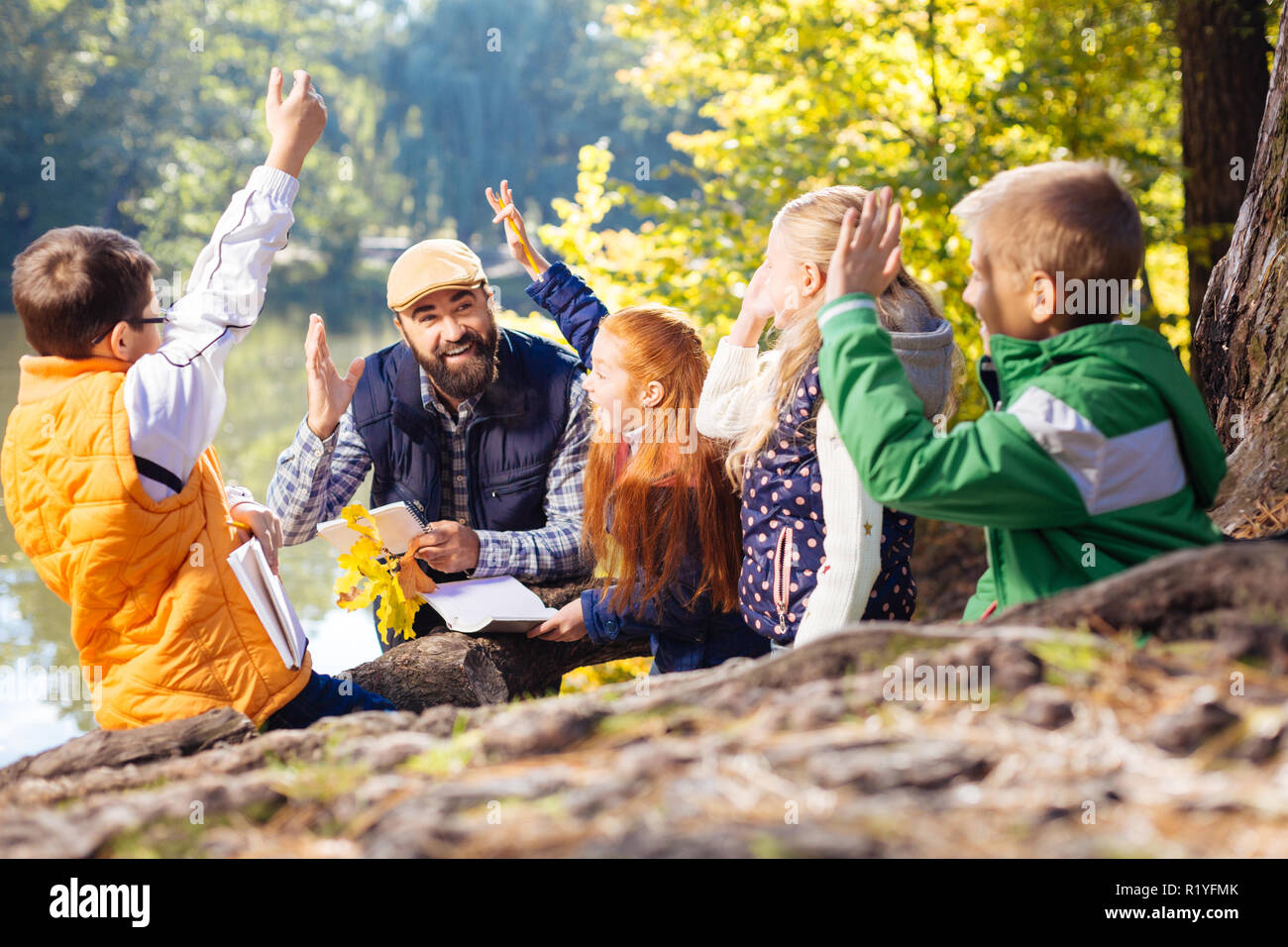 Joyful smart children raising their hands up Stock Photo - Alamy