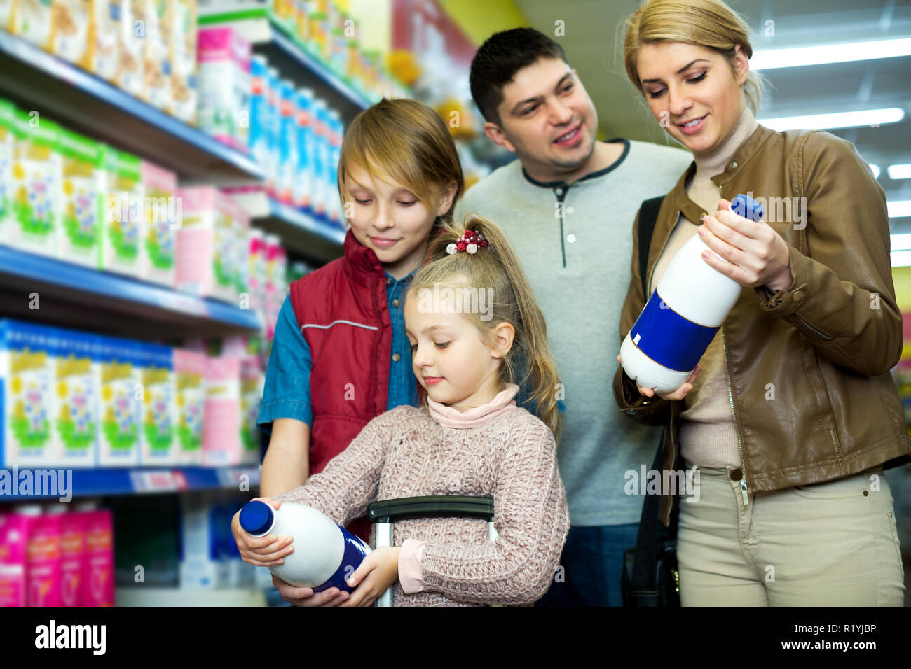 Happy ordinary family of customers with children purchasing milk in ...
