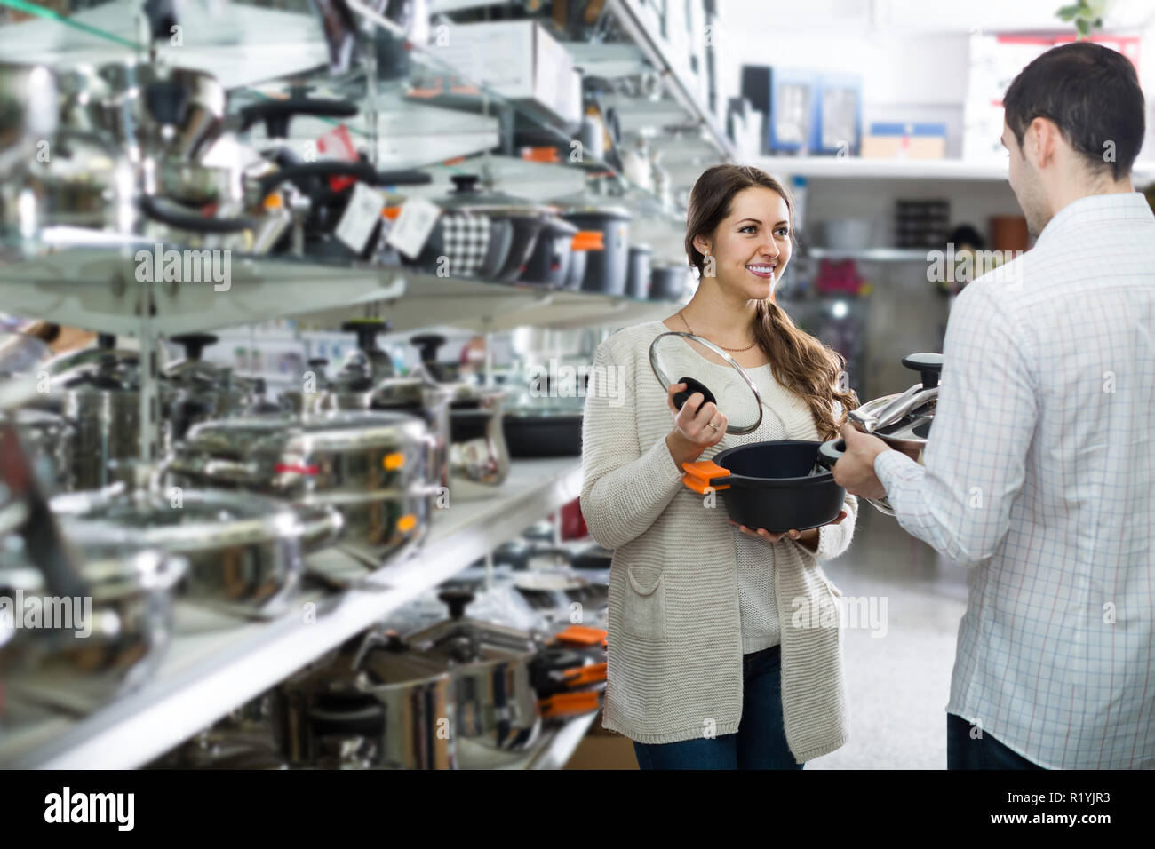happy spanish couple chooses pans in shop cookware.focus on girl Stock ...