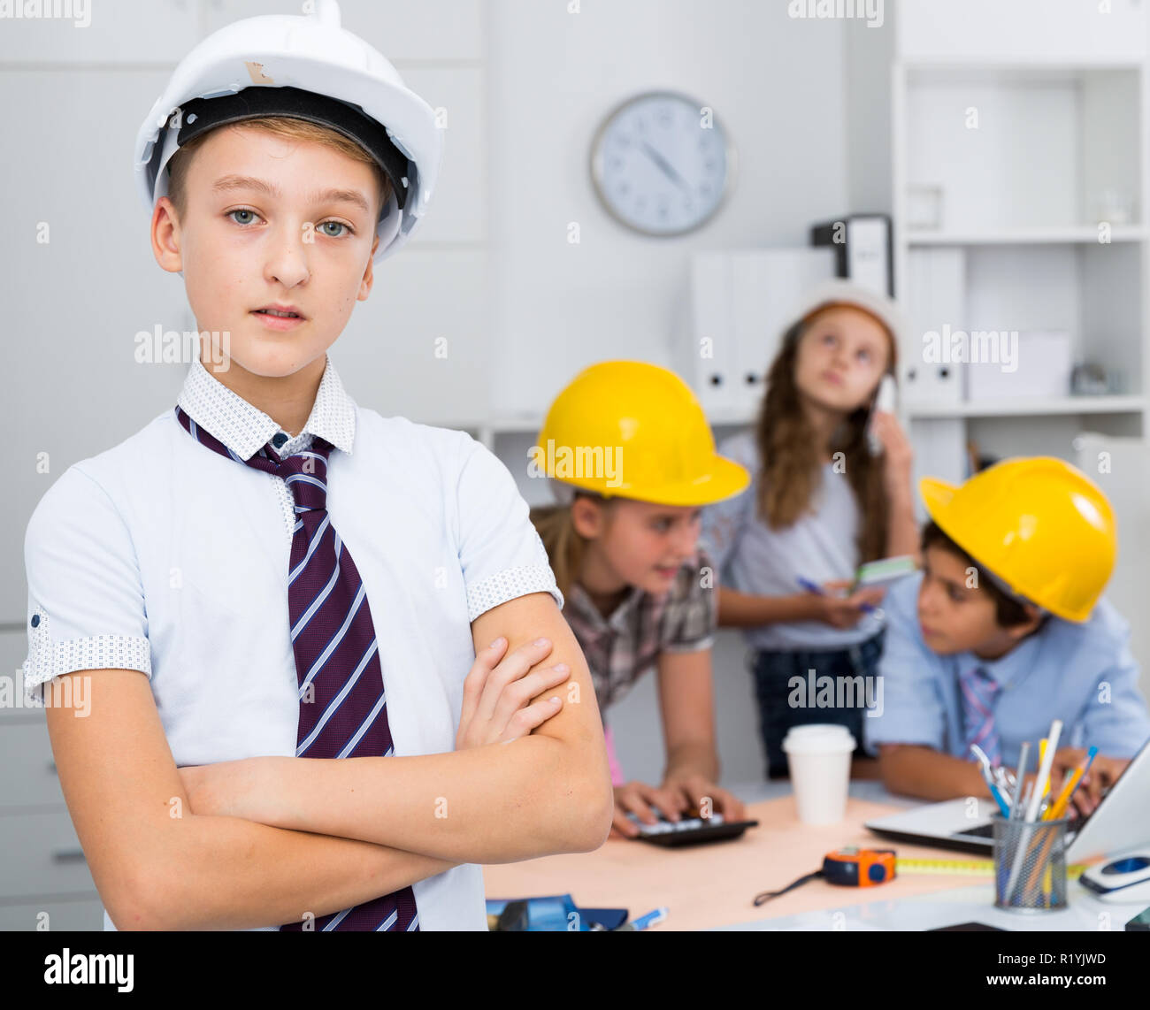 Teenager boy engineer and children with plan and notebook in the office ...