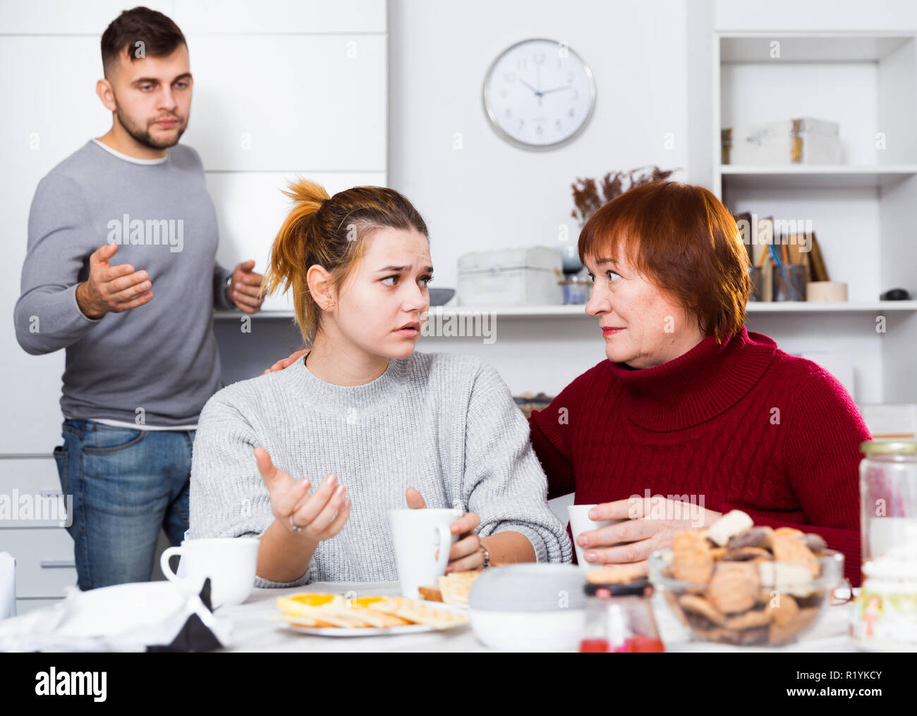 Senior woman calming chagrined girl during her quarrel with boyfriend ...