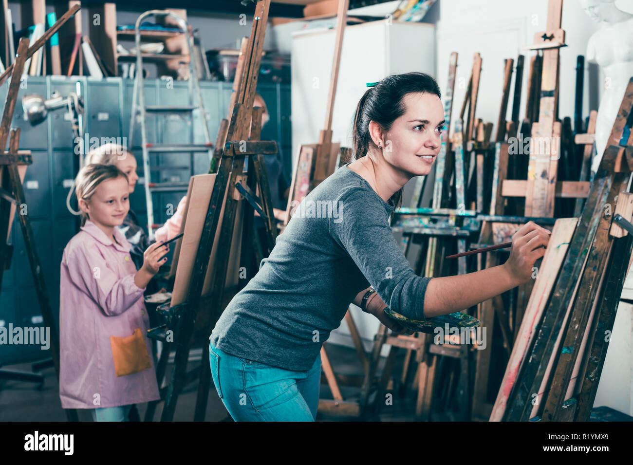Positive woman teacher giving workshop session during painting class at ...