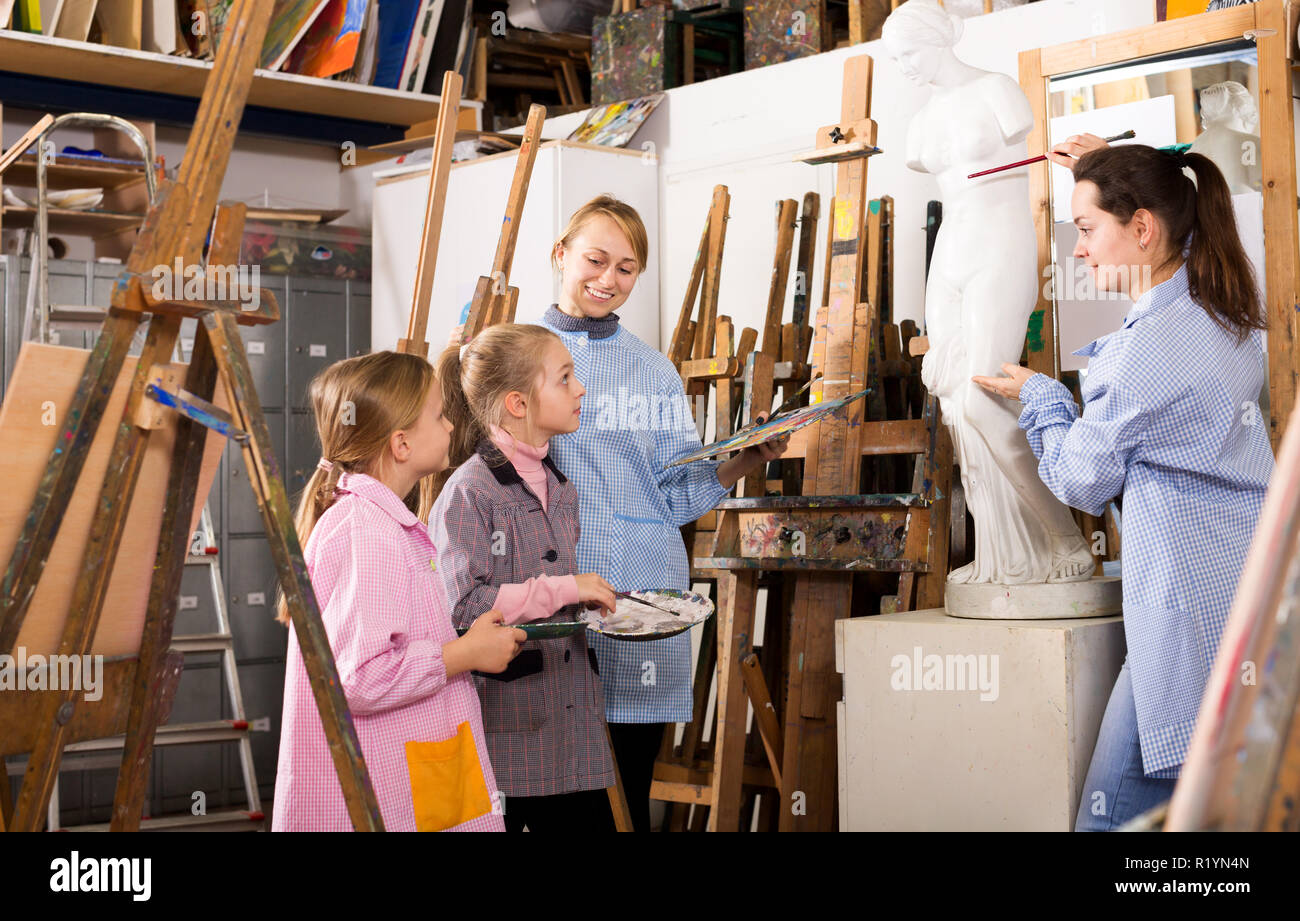 Happy young female teacher explaining painting techniques during ...