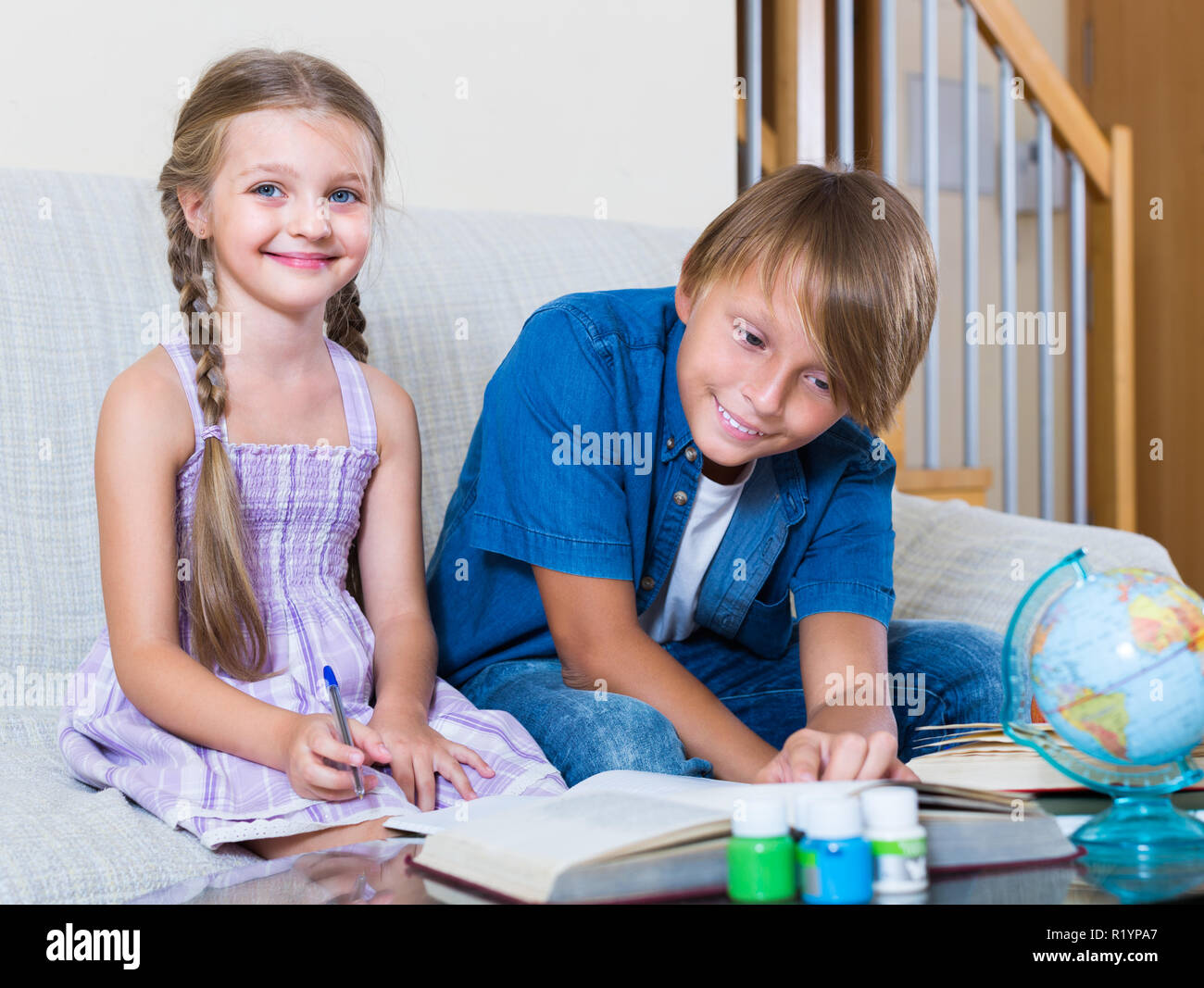 Teenage boy and younger sister learning with books indoors Stock Photo ...