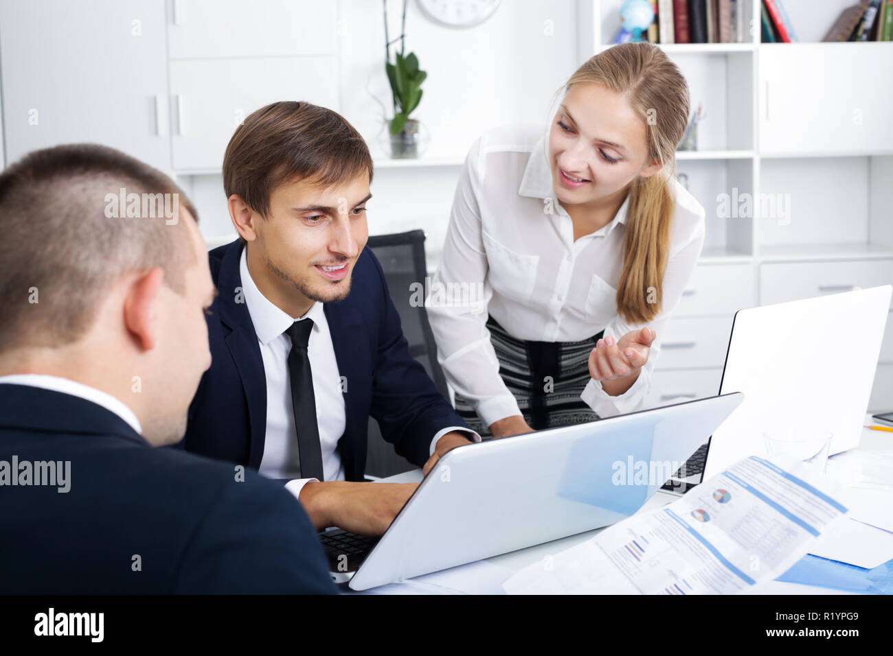 Three young coworkers working on document paper together in firm office ...