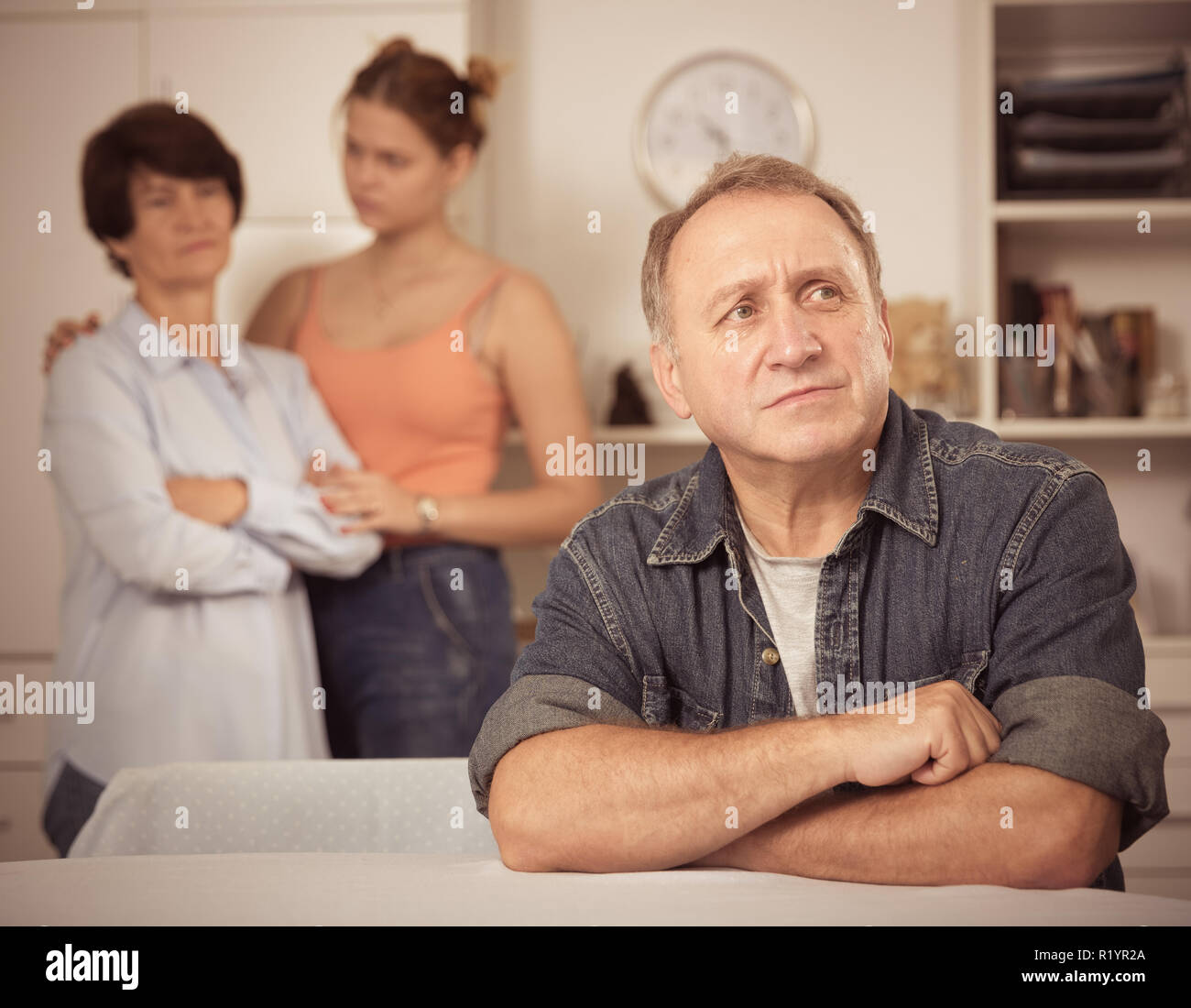 Woman and her daughter are sympathying their sad father who is sitting ...