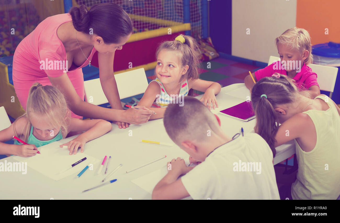 Glad children drawing pencils on lesson in elementary school class with ...