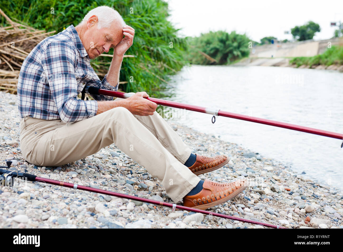 Cheerful aged man with fishing rod sitting and relaxing by lakeside Stock Photo - Alamy