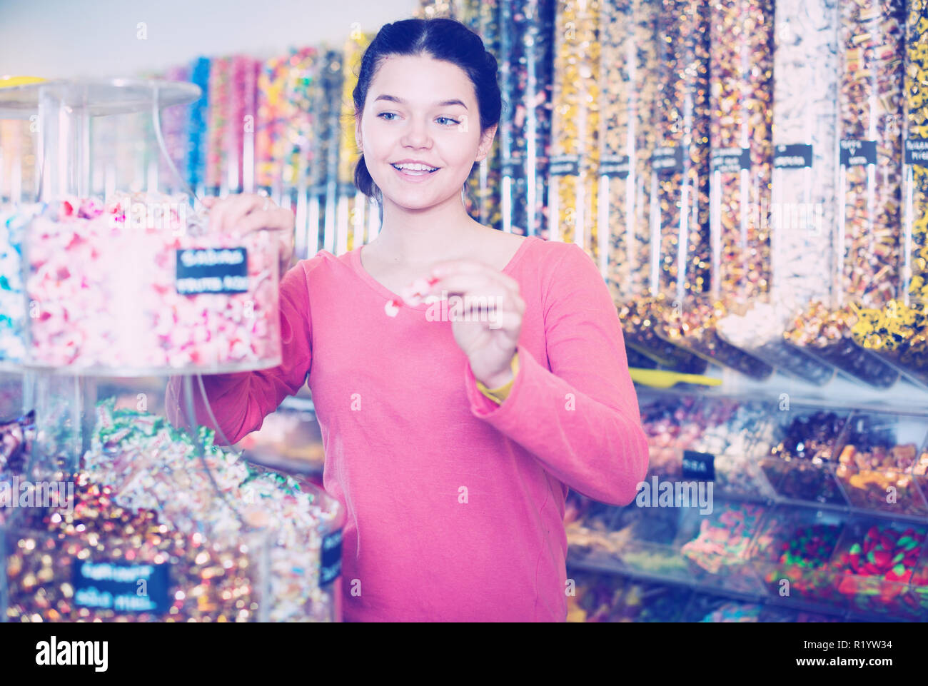 Happy brunette girl buying candies at shop Stock Photo - Alamy