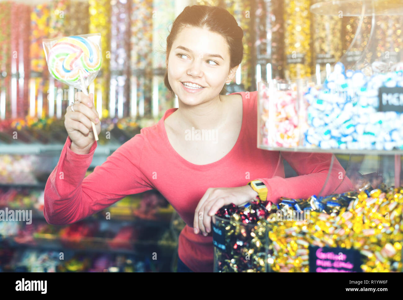 Happy brunette girl buying candies at shop Stock Photo - Alamy