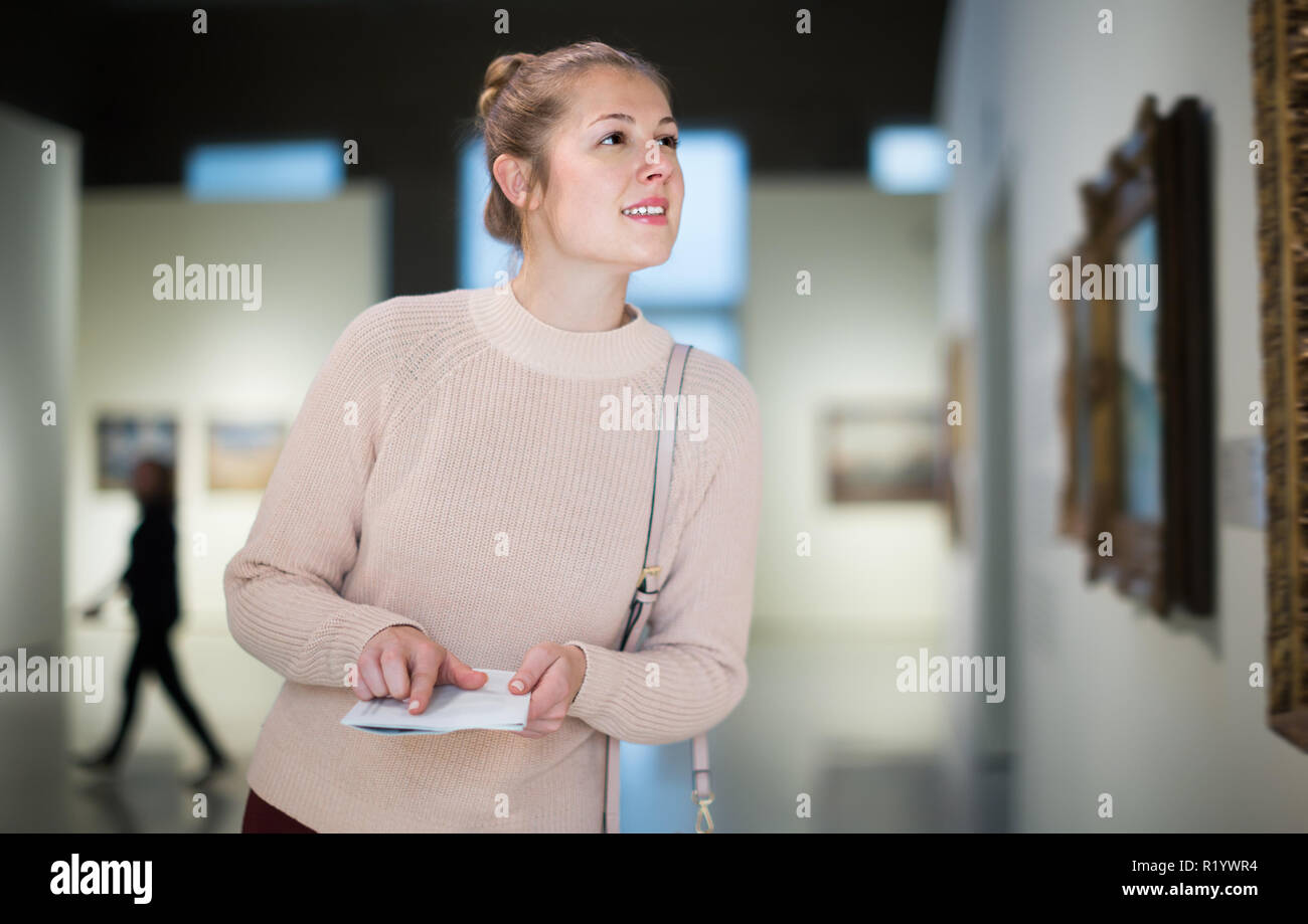 Portrait of attractive woman looking at pictures and amaze in museum ...