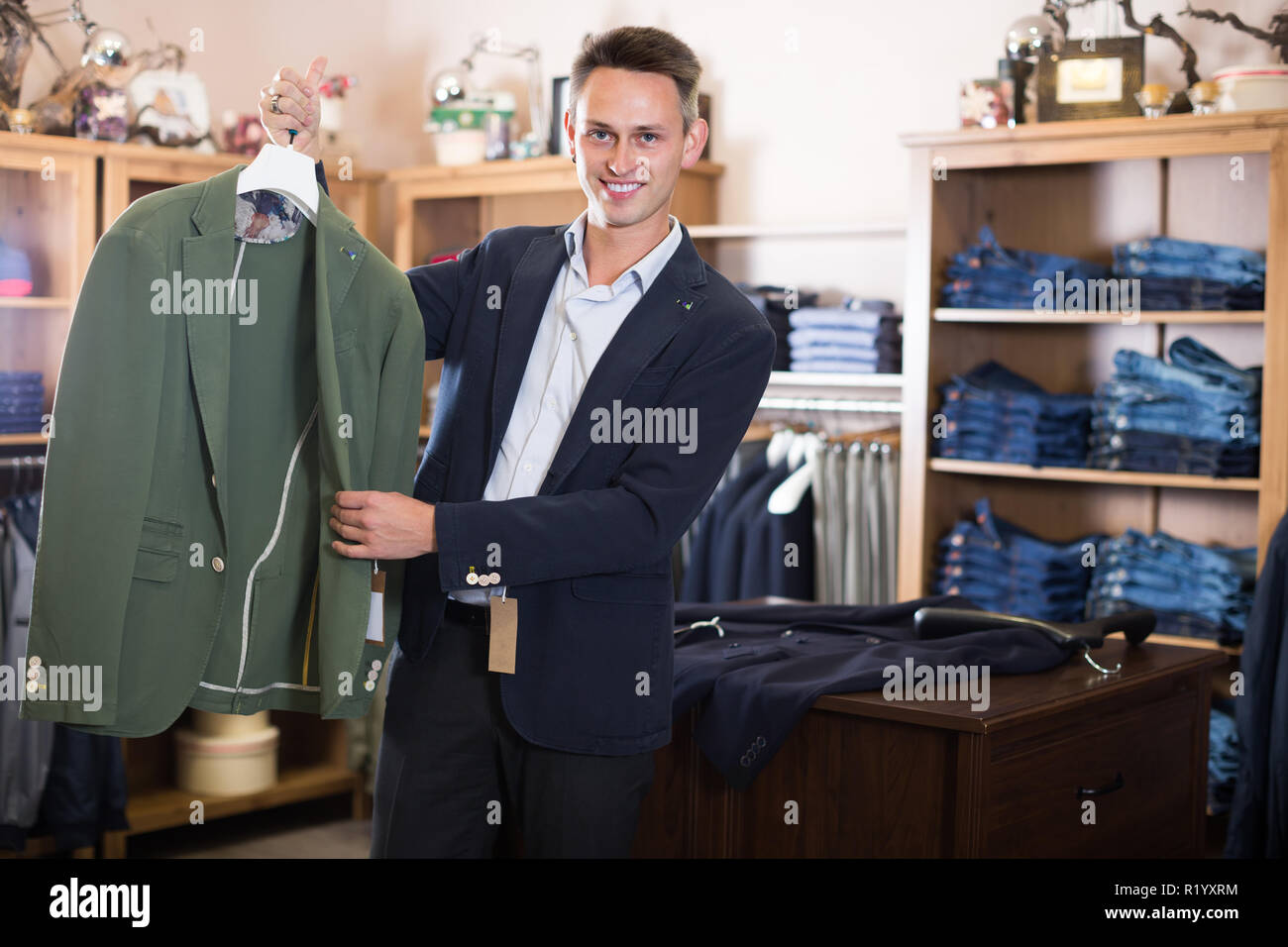 Smiling guy shopper choosing new jacket in men’s store Stock Photo - Alamy