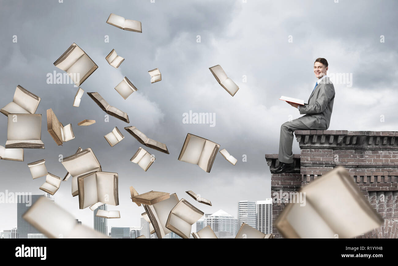 Man on roof reading book and many of them flying in air Stock Photo - Alamy