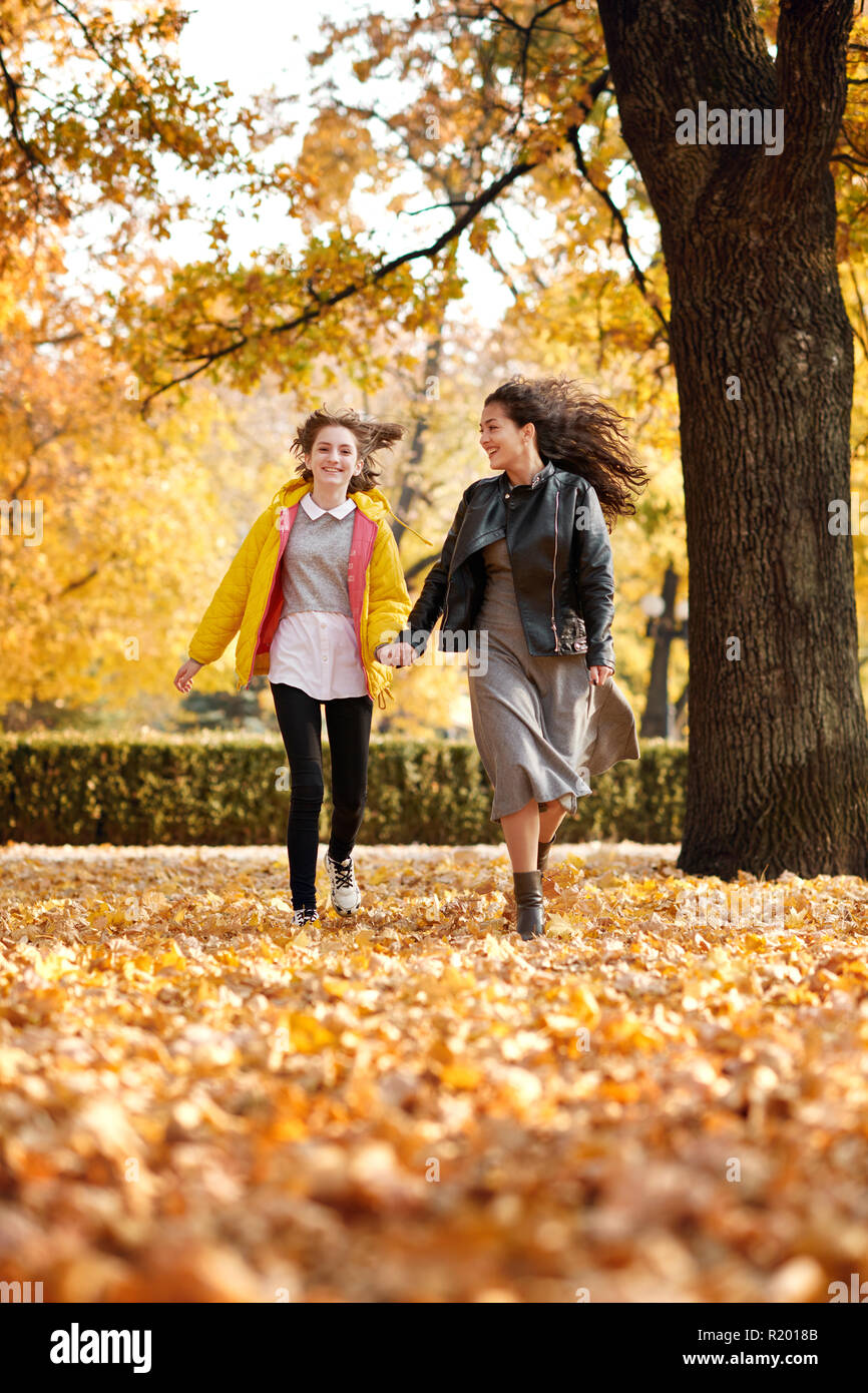 Two happy girls running in autumn city park Stock Photo - Alamy