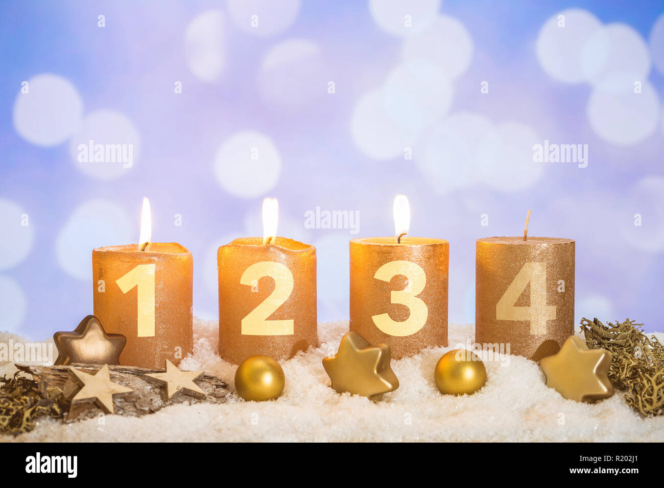 Four numbered gold advent candles with three candles lit and christmas ...