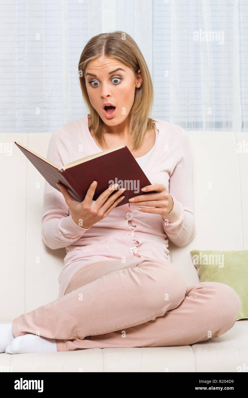 Surprised woman reading book Stock Photo - Alamy