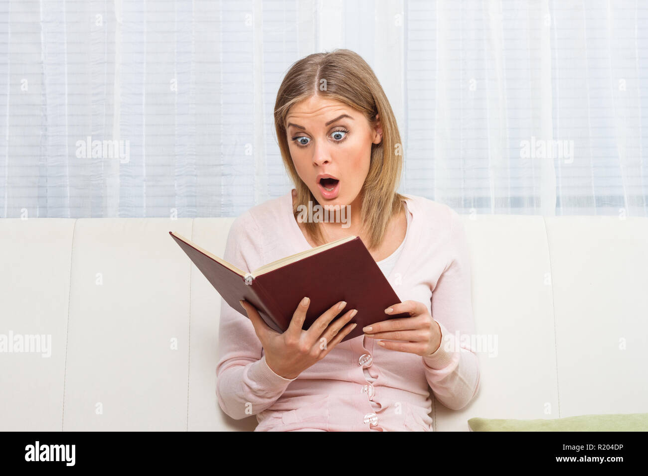 Surprised woman reading book Stock Photo - Alamy