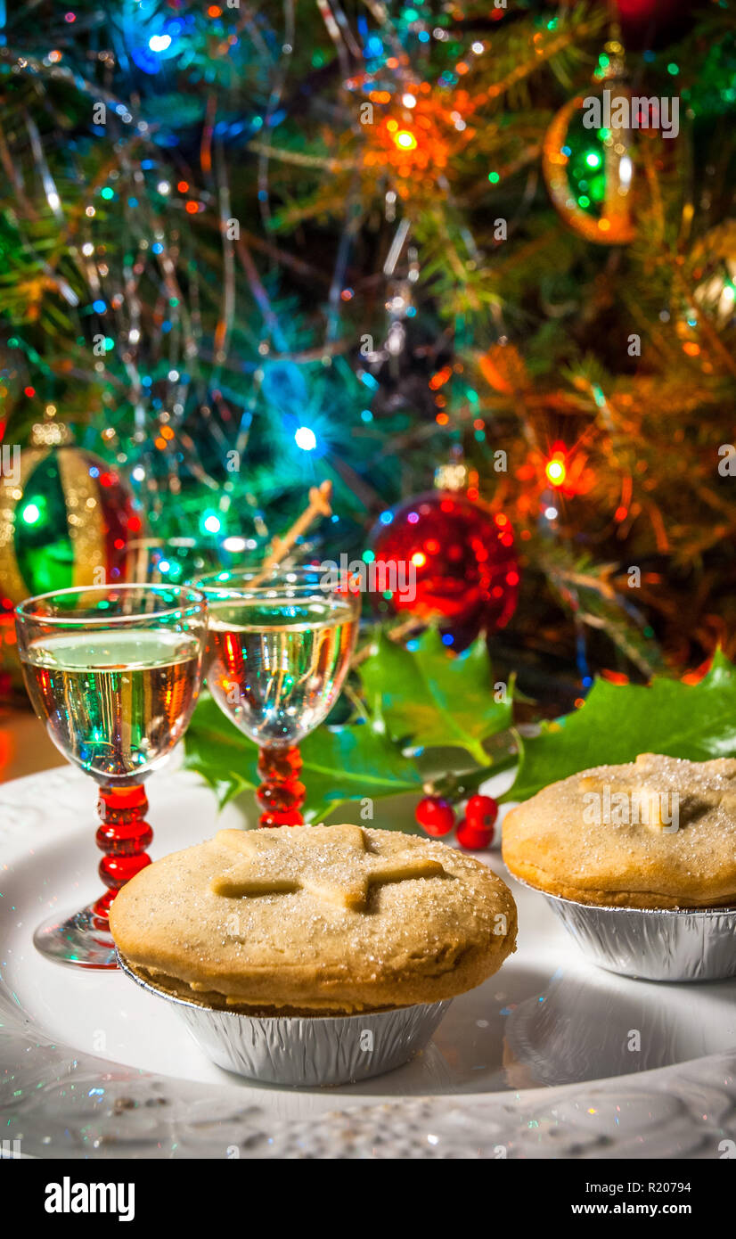 A festive plate of mince pies and sherry with Christmas tree and lights ...