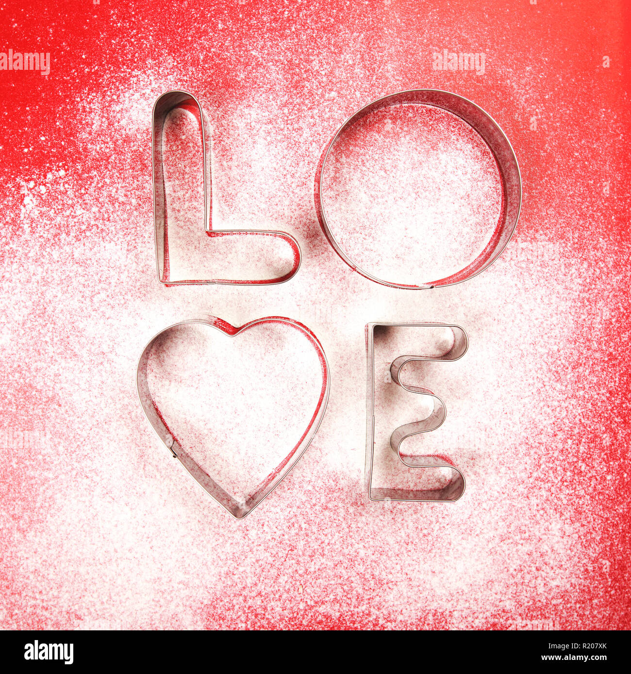 Cookie cutters shaped in Love with flour lying on red background ...