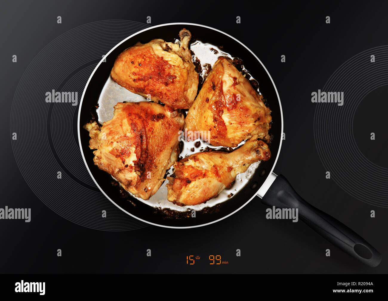 chicken thighs in a frying pan which is on an induction cooker Stock ...