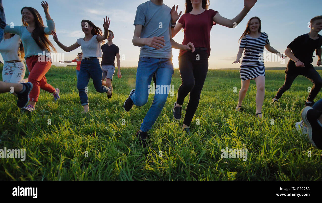 Group of friends running happily together in the grass Stock Photo - Alamy