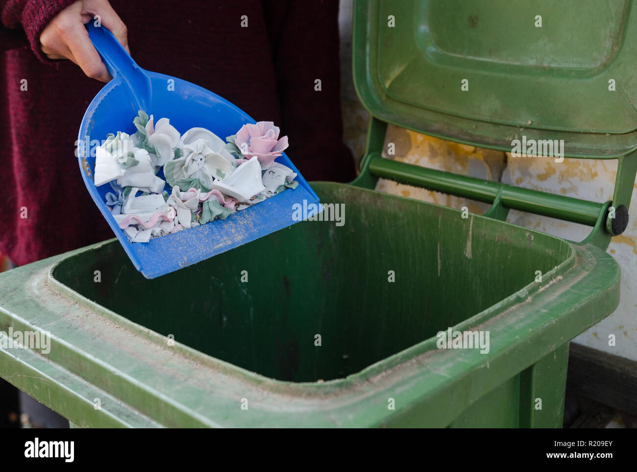 Broken porcelain tiles on a shovel next to the trash can - cleaning ...
