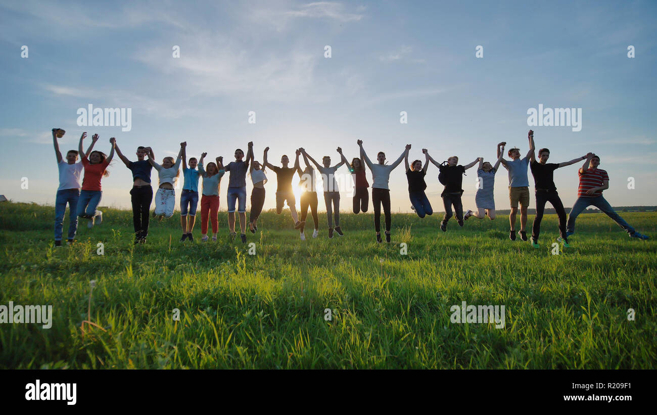 Group of best friends and students jumping outdoors. Sunset with ...